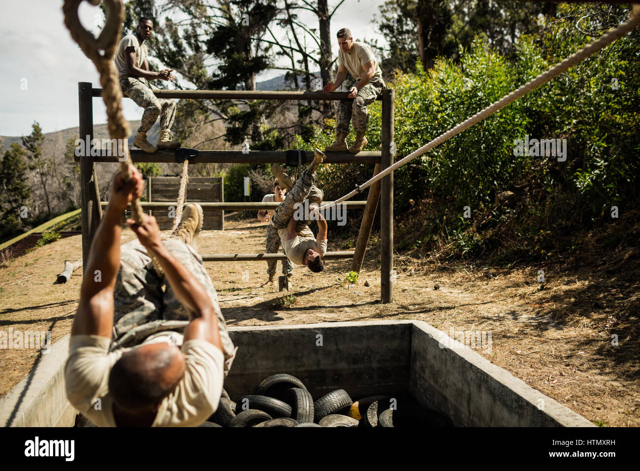 Young military soldiers practicing rope climbing during obstacle course ...