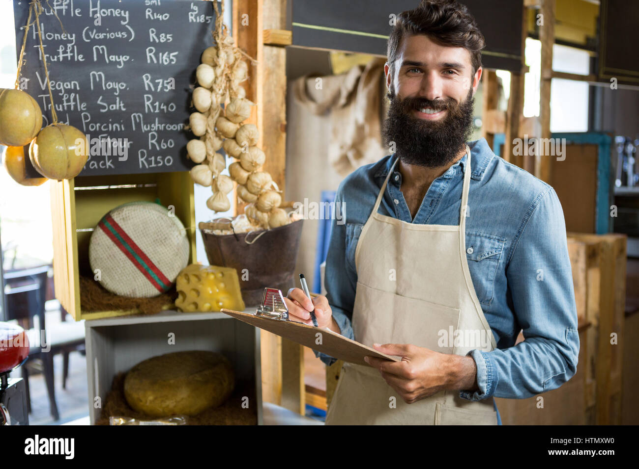 Portrait of salesman writing on clipboard at counter in grocery shop in ...