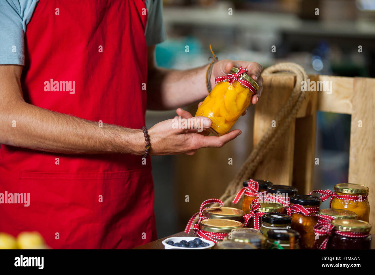 Mid-section of staff checking pickle jar at counter in market Stock ...