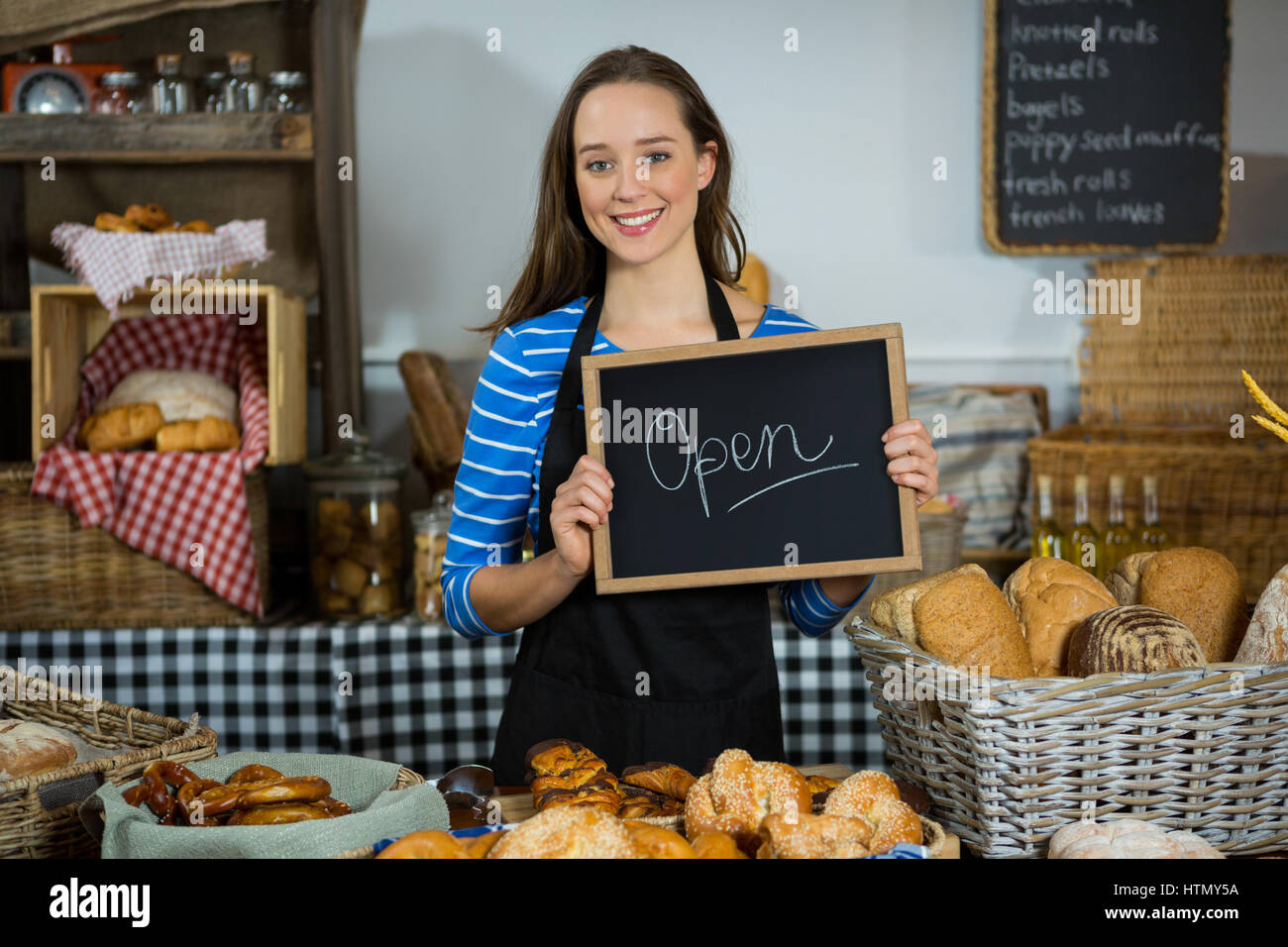 Portrait of smiling female staff holding chalkboard with open sign at ...