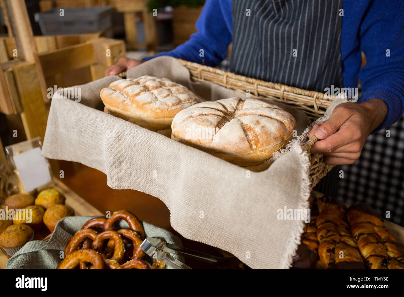 Mid section of staff holding wicker basket of breads at counter in ...