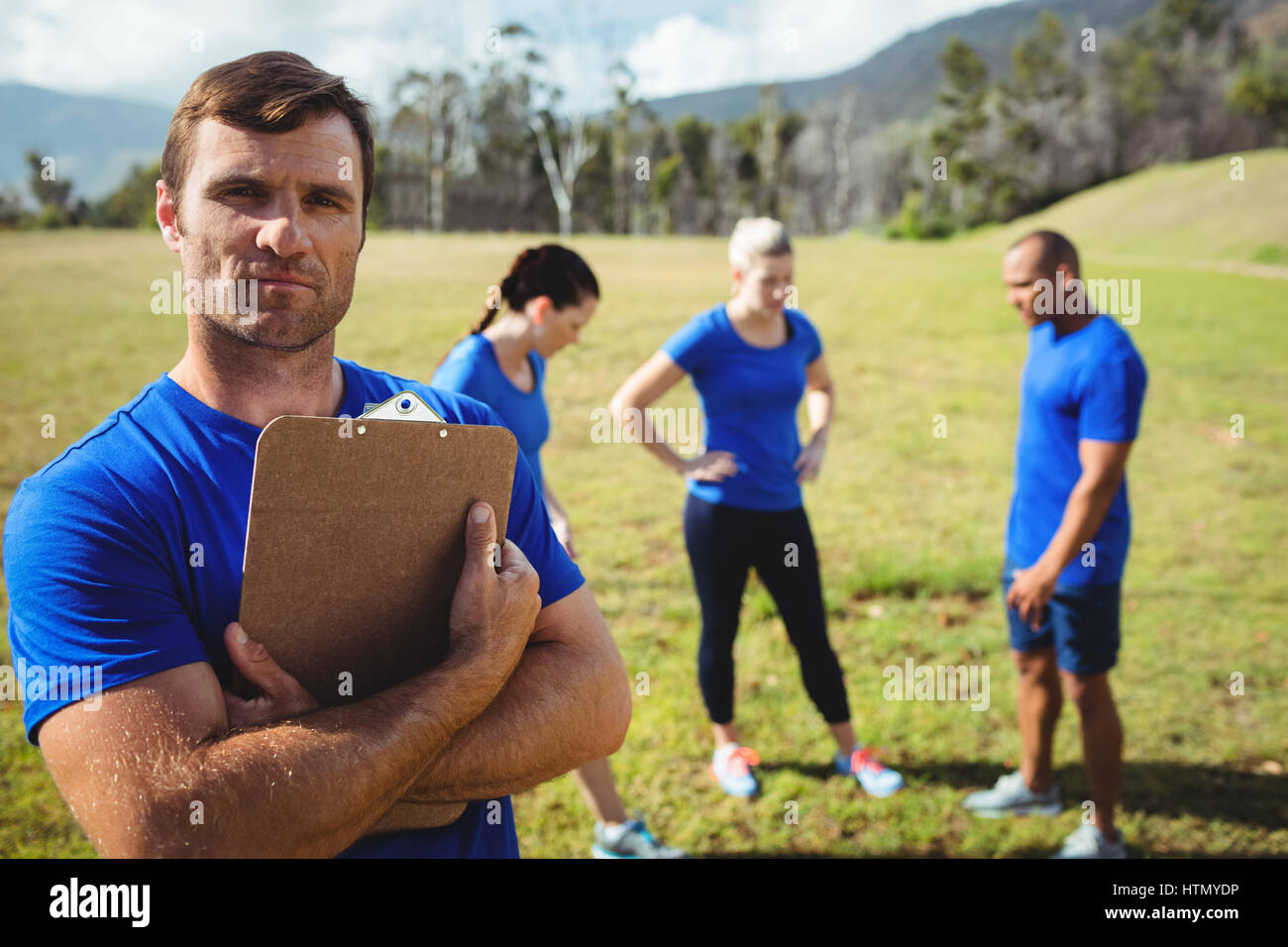 Fit man standing and holding a clipboard in boot camp on a sunny day ...