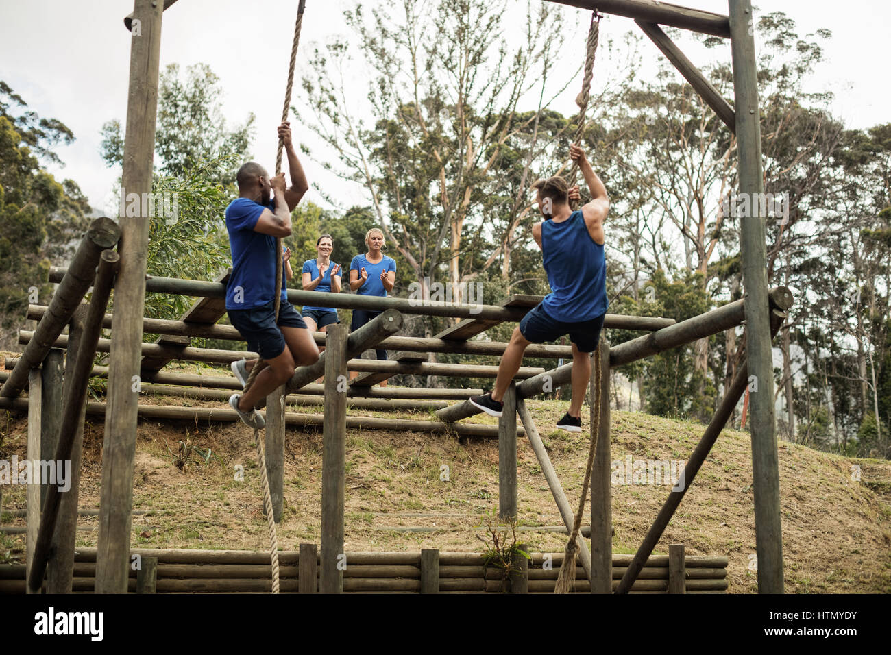 Fit men climbing down the rope during obstacle course in boot camp ...