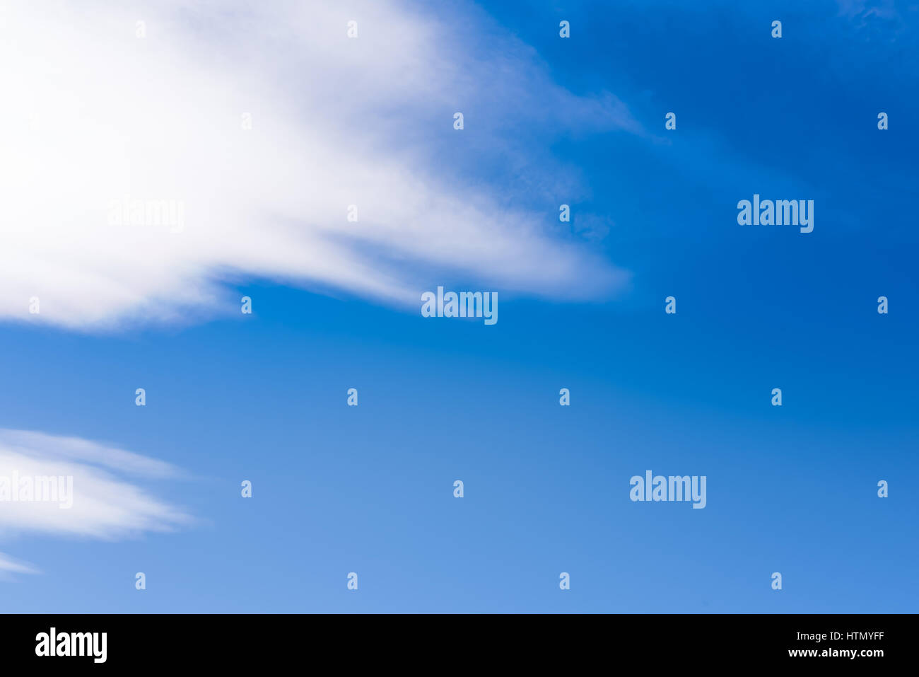 Blue saturated sky background with diagonal clouds on the left side ...