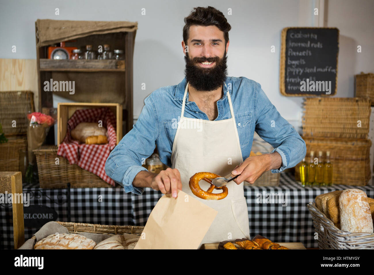 Portrait of male staff packing pretzel in paper bag in market Stock ...