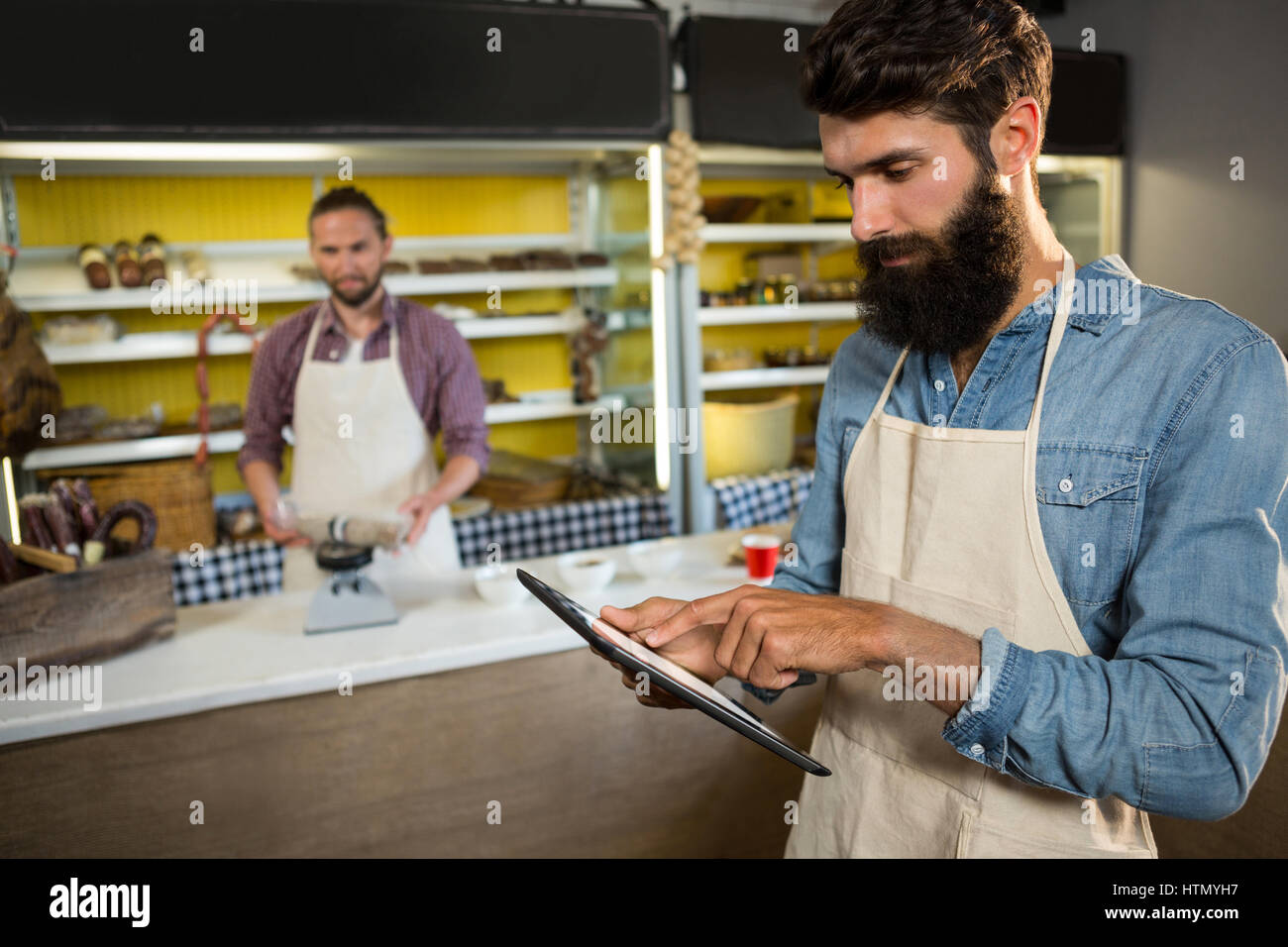 Portrait of smiling male staff using digital tablet near counter in ...