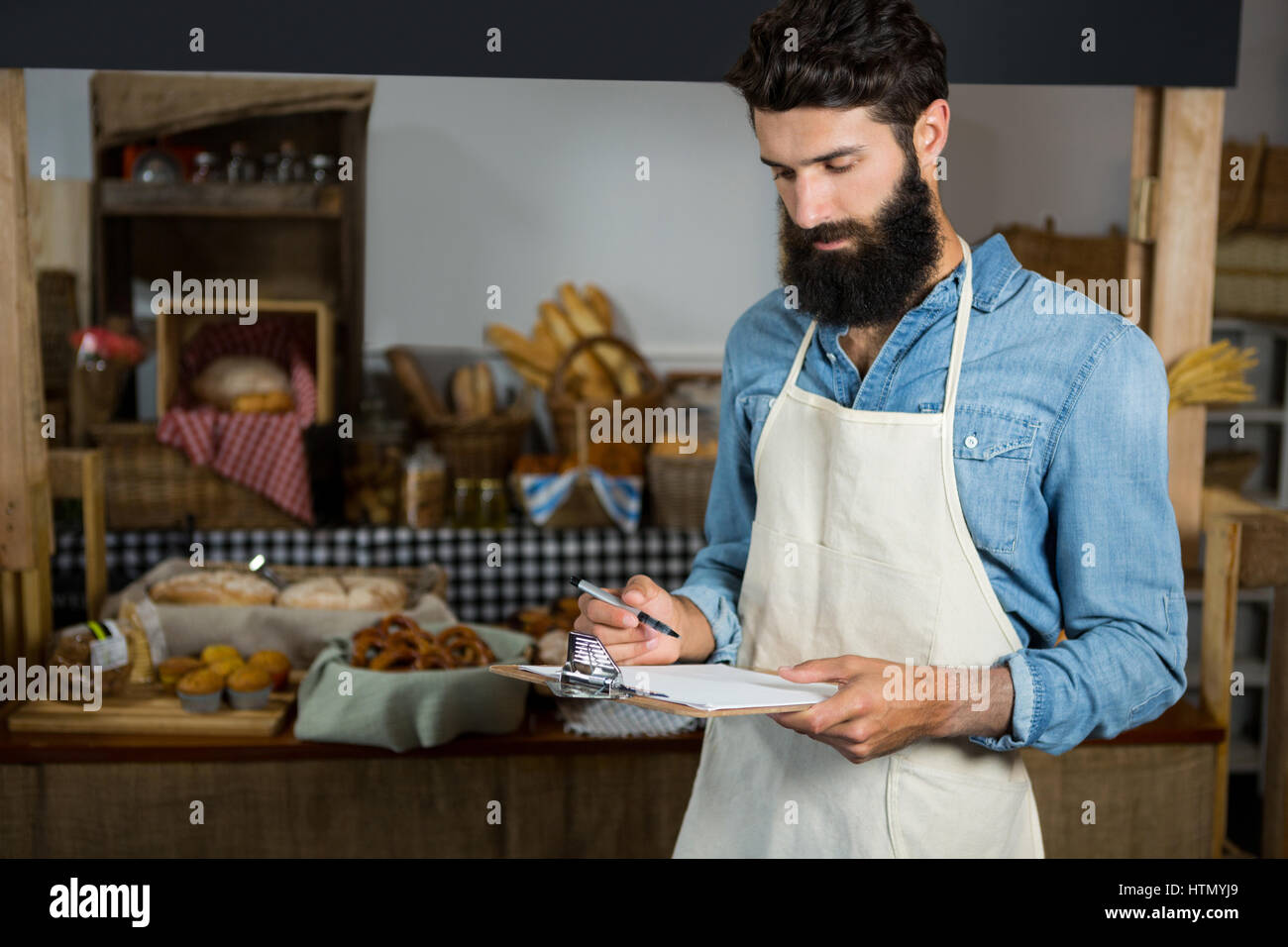Salesman writing on clipboard at counter in grocery shop Stock Photo ...