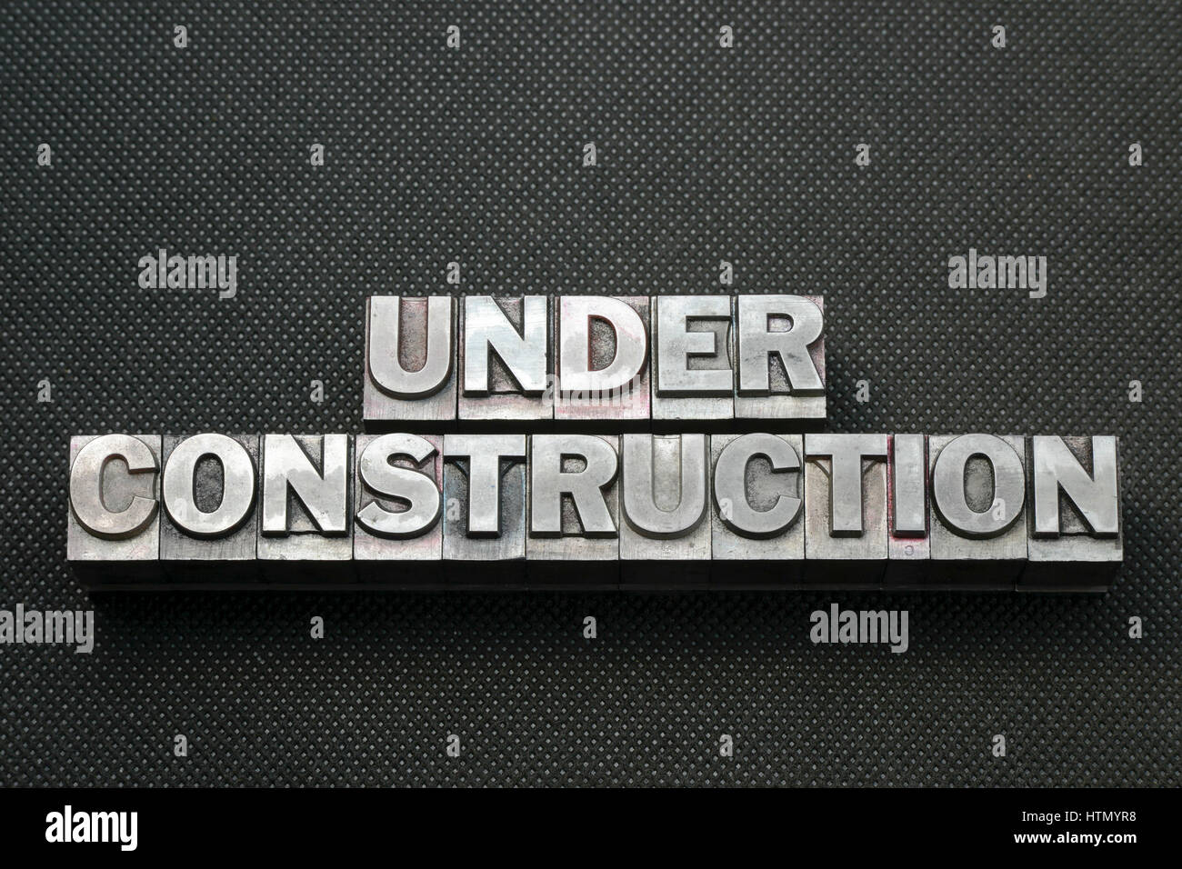under construction phrase made from metallic letterpress blocks on ...