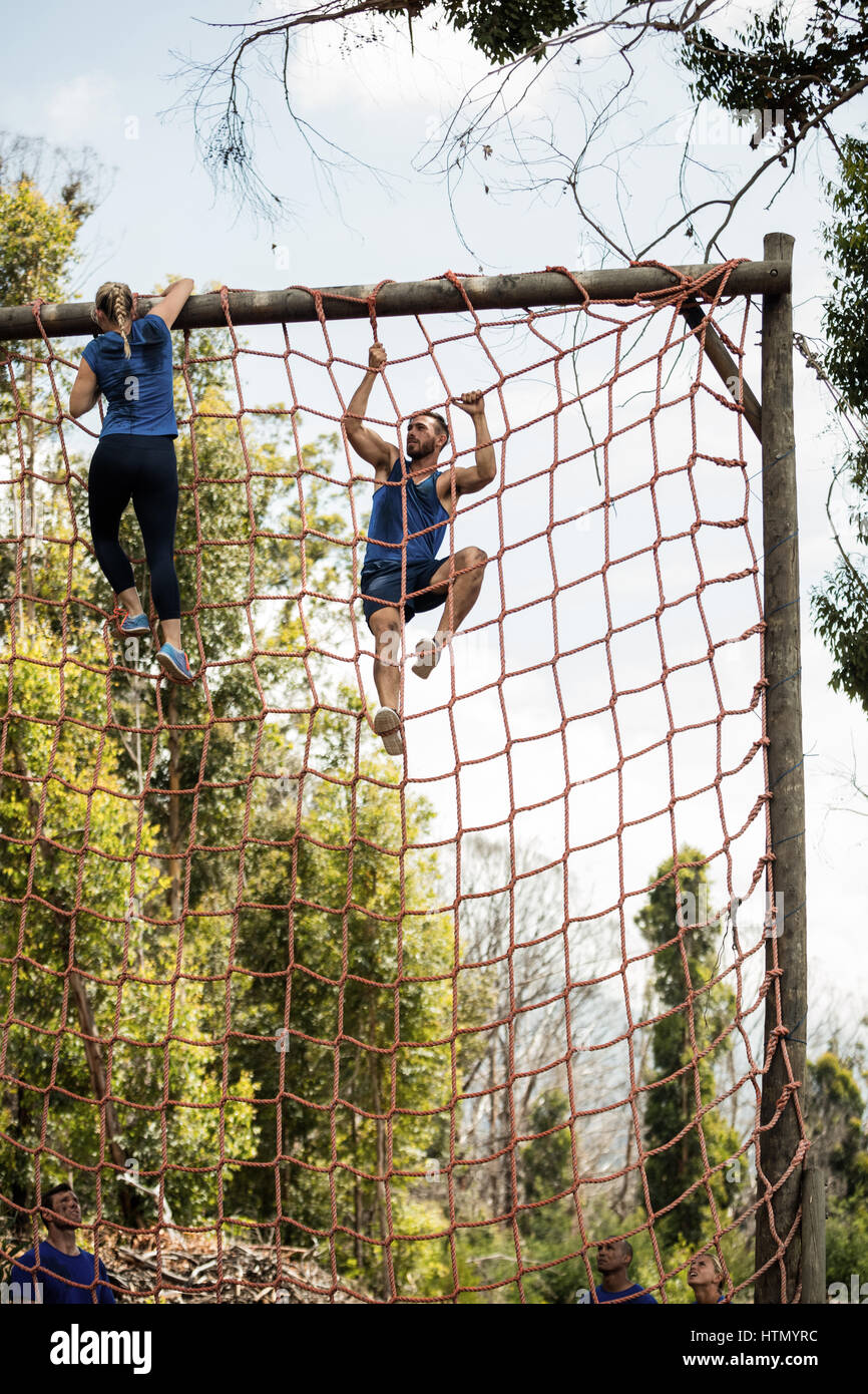 People climbing a net during obstacle course in boot camp Stock Photo ...