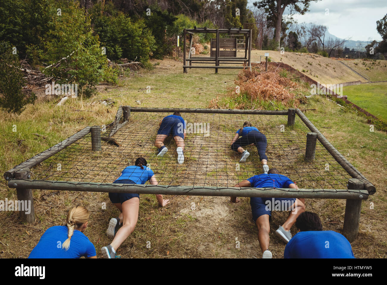 Fit people crawling under the net during obstacle course in bootcamp ...