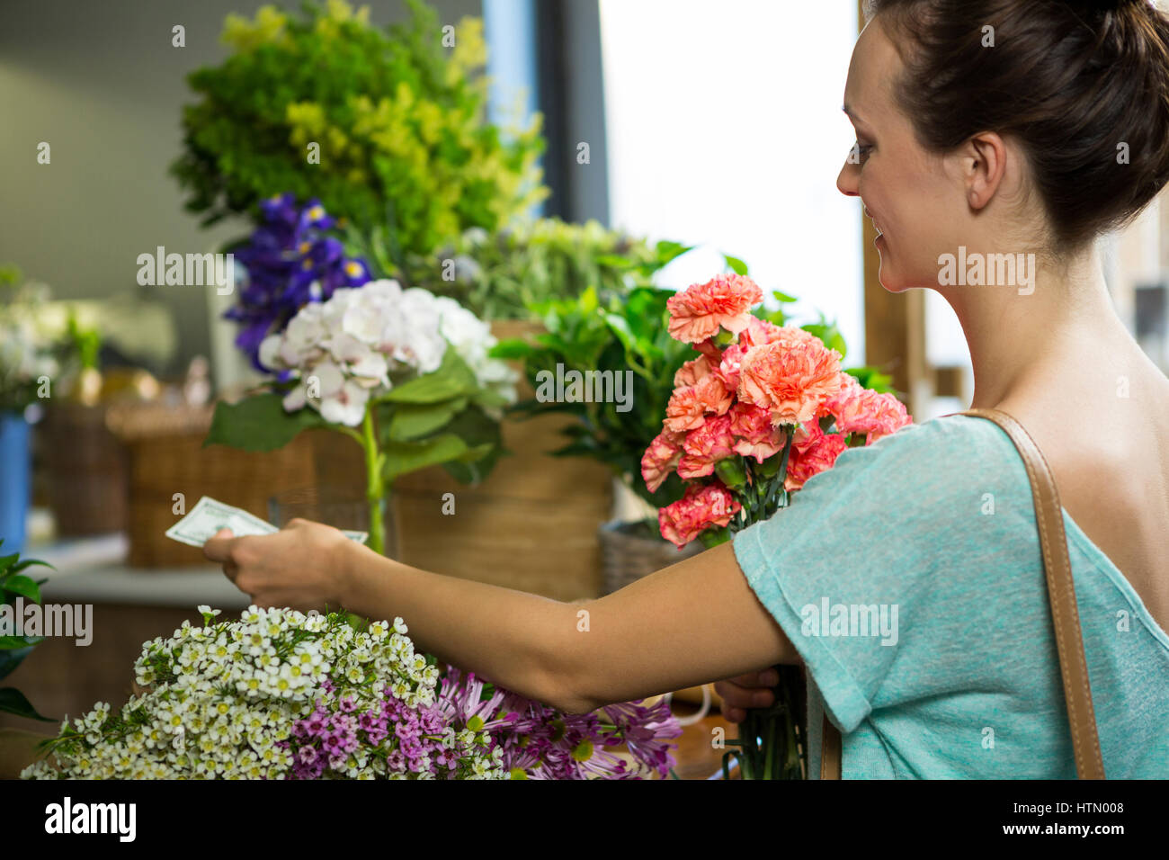 Woman making payment at counter in flower shop Stock Photo - Alamy