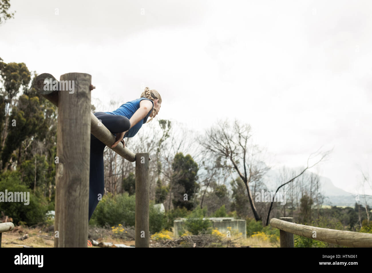 Woman jumping over the hurdles during obstacle course in boot camp ...