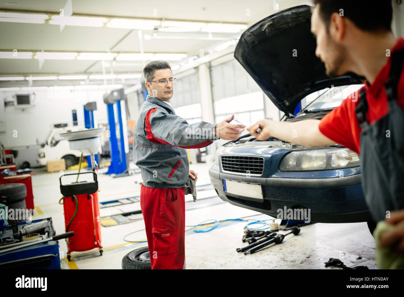 Car mechanic working as a team fixing car Stock Photo - Alamy