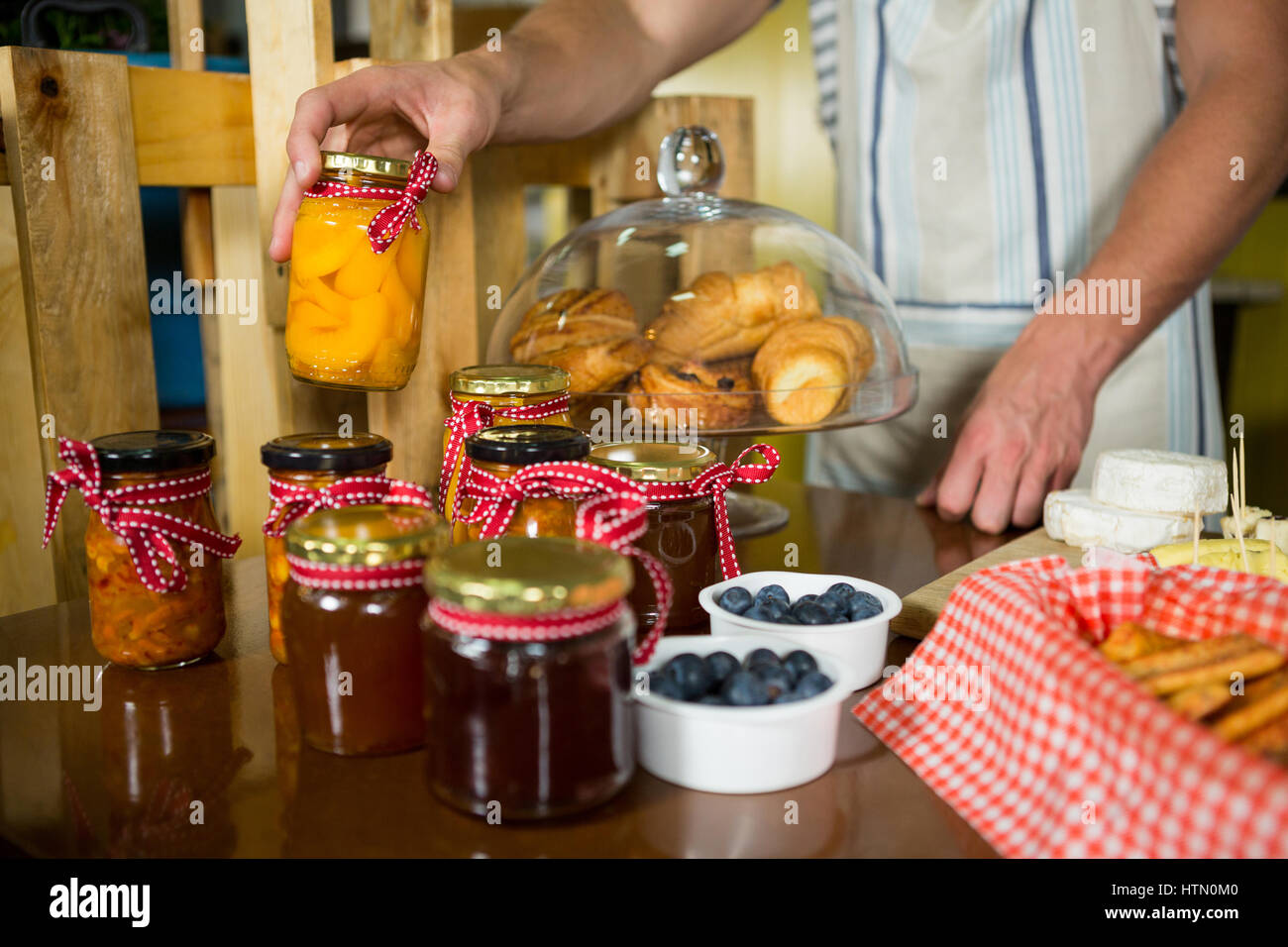 Shop assistant arranging jam and pickle jars in grocery shop Stock ...