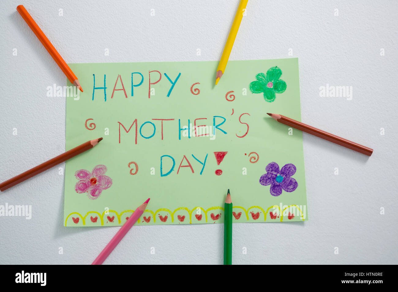 Color pencil arranged around mothers day greetings card on white ...