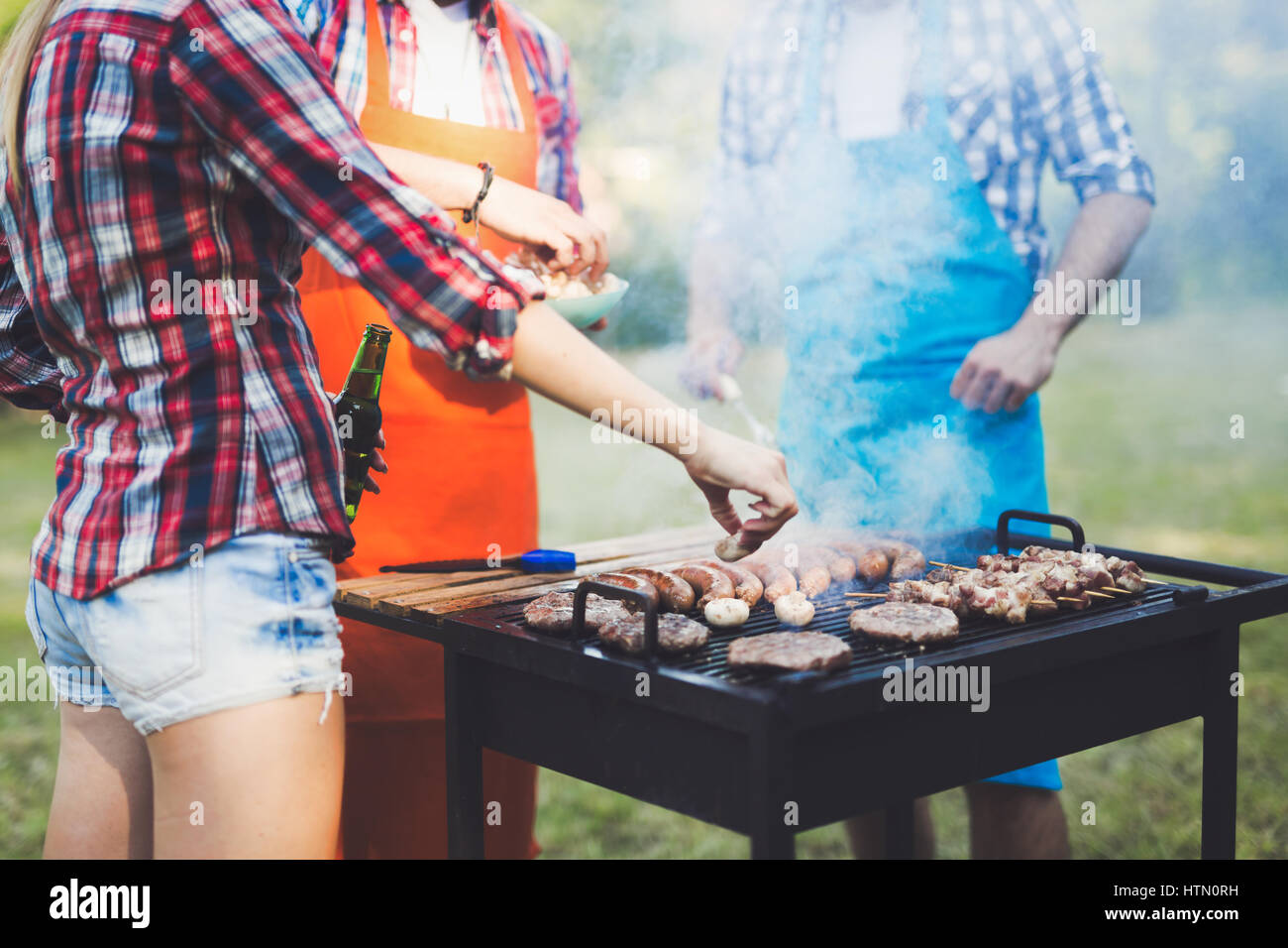 Friends having fun grilling meat enjoying bbq party Stock Photo - Alamy