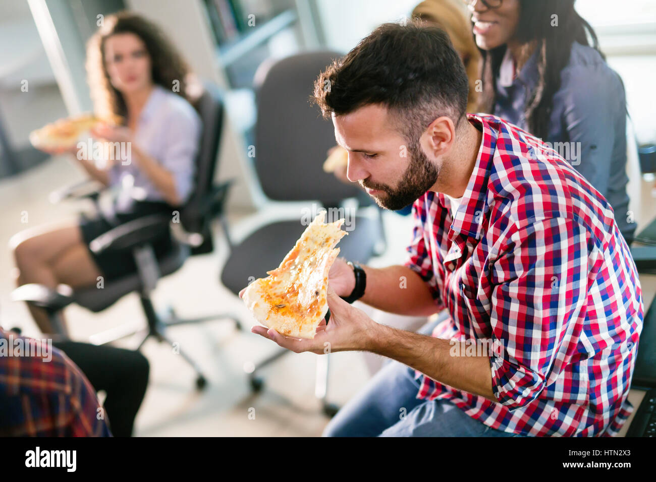 Coworkers eating pizza during work break at office Stock Photo - Alamy
