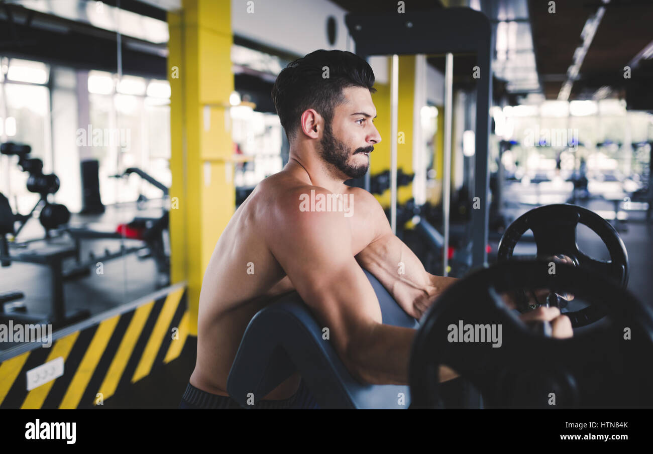 Determined male working out in gym lifting weights Stock Photo - Alamy