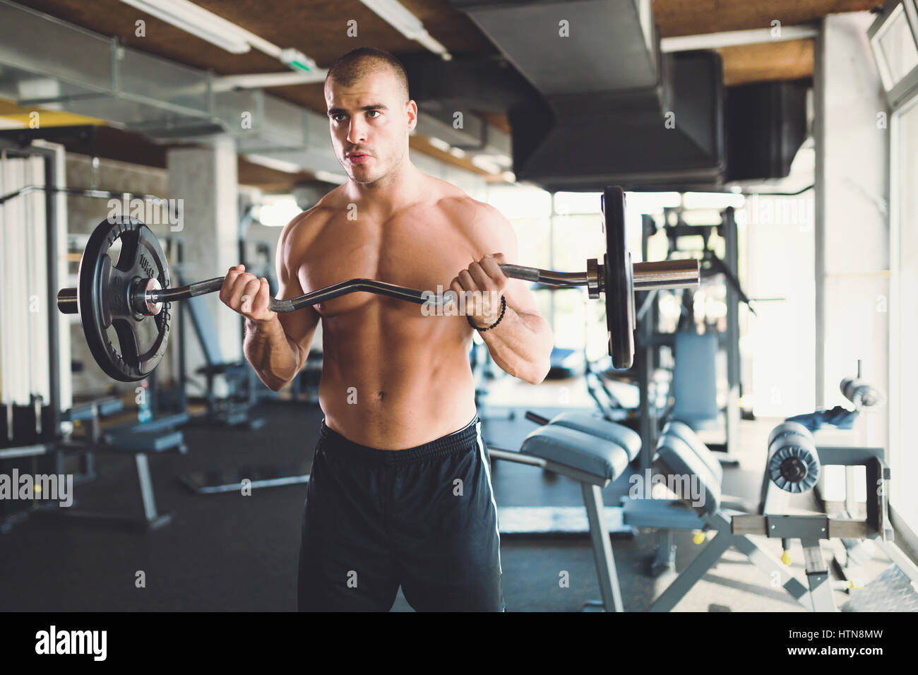 Determined male working out in gym lifting weights Stock Photo - Alamy