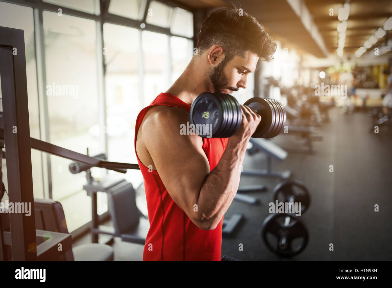 Determined male working out in gym lifting weights Stock Photo - Alamy