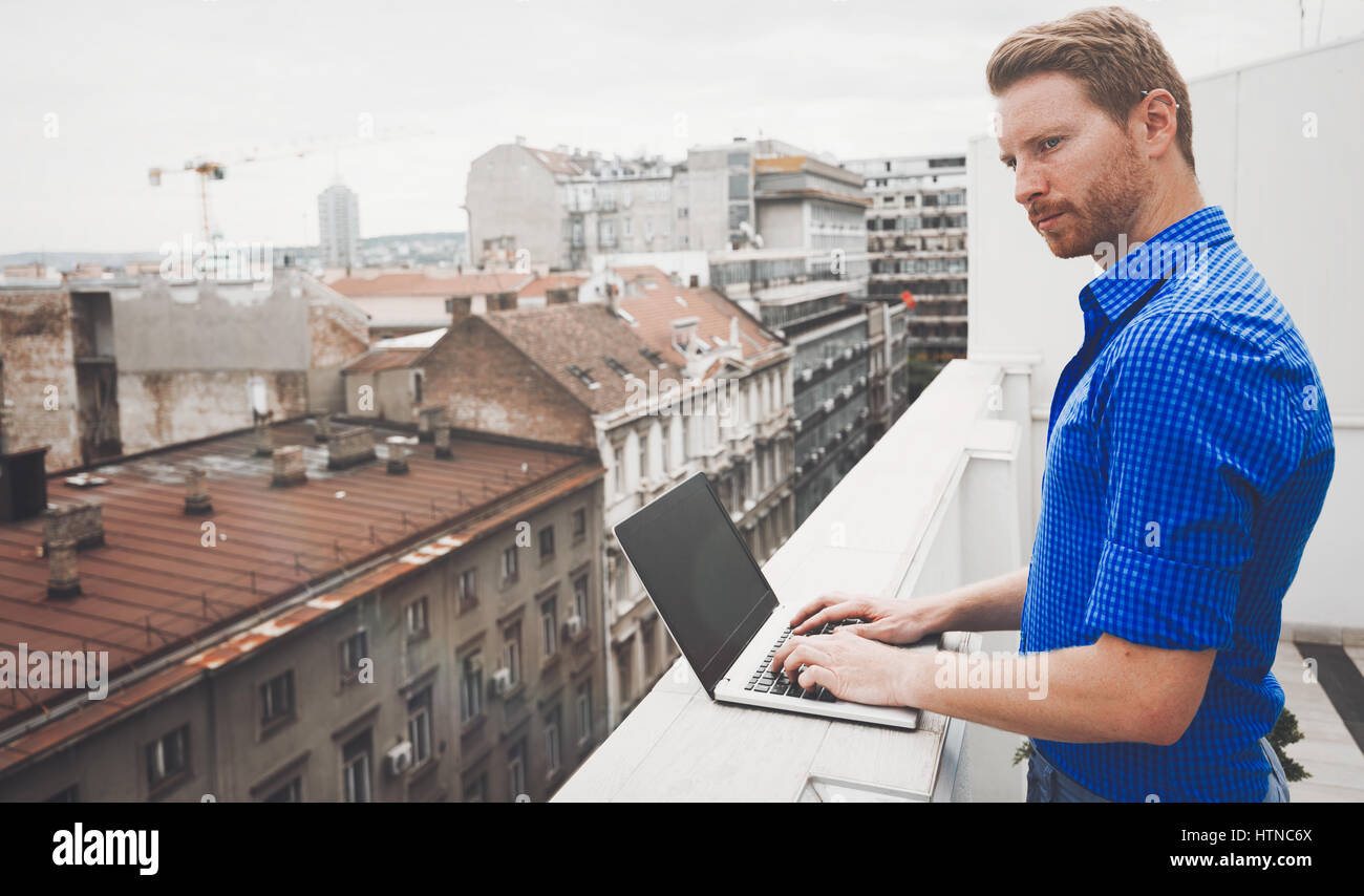 Business person using laptop outdoors on rooftop Stock Photo - Alamy