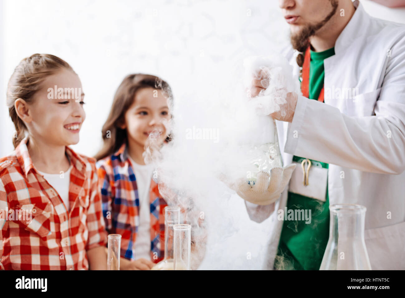 Fascinated by the experiment. Delighted positive cute girls smiling and ...