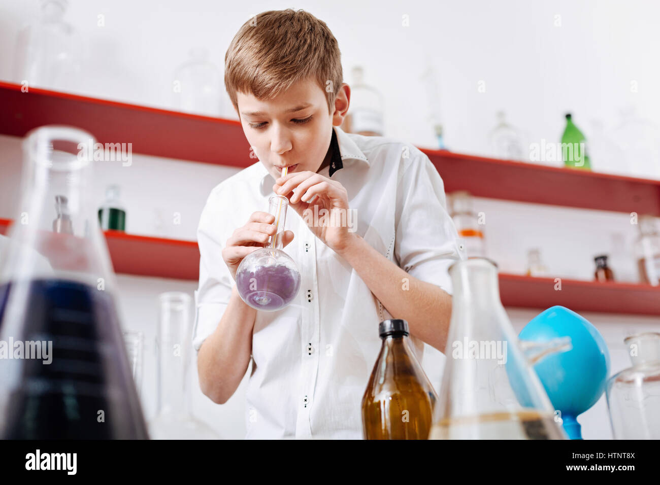 Young chemist. Smart curious nice boy using chemical equipment and ...