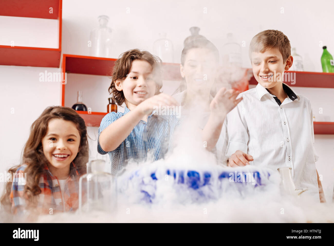 Interesting experiments. Cheerful positive curious children standing at ...