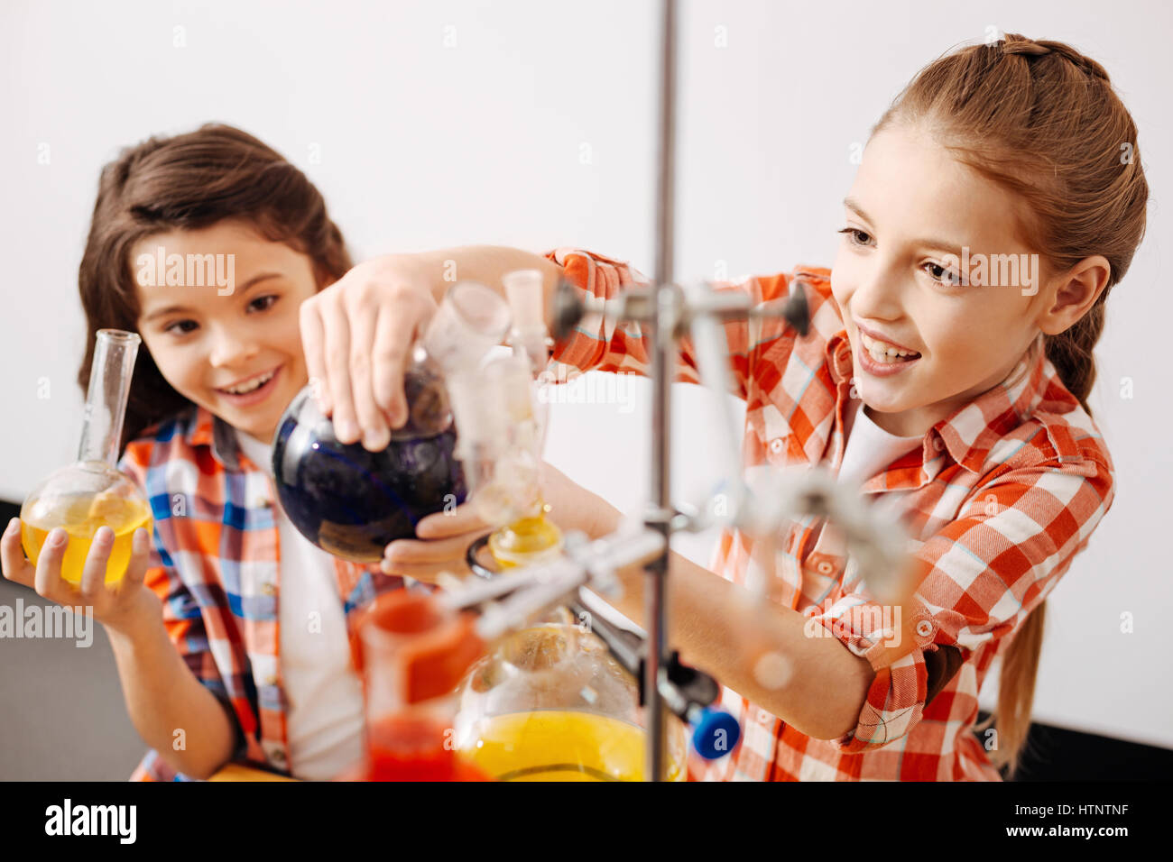 Science for children. Delighted pretty nice girls smiling and enjoying ...