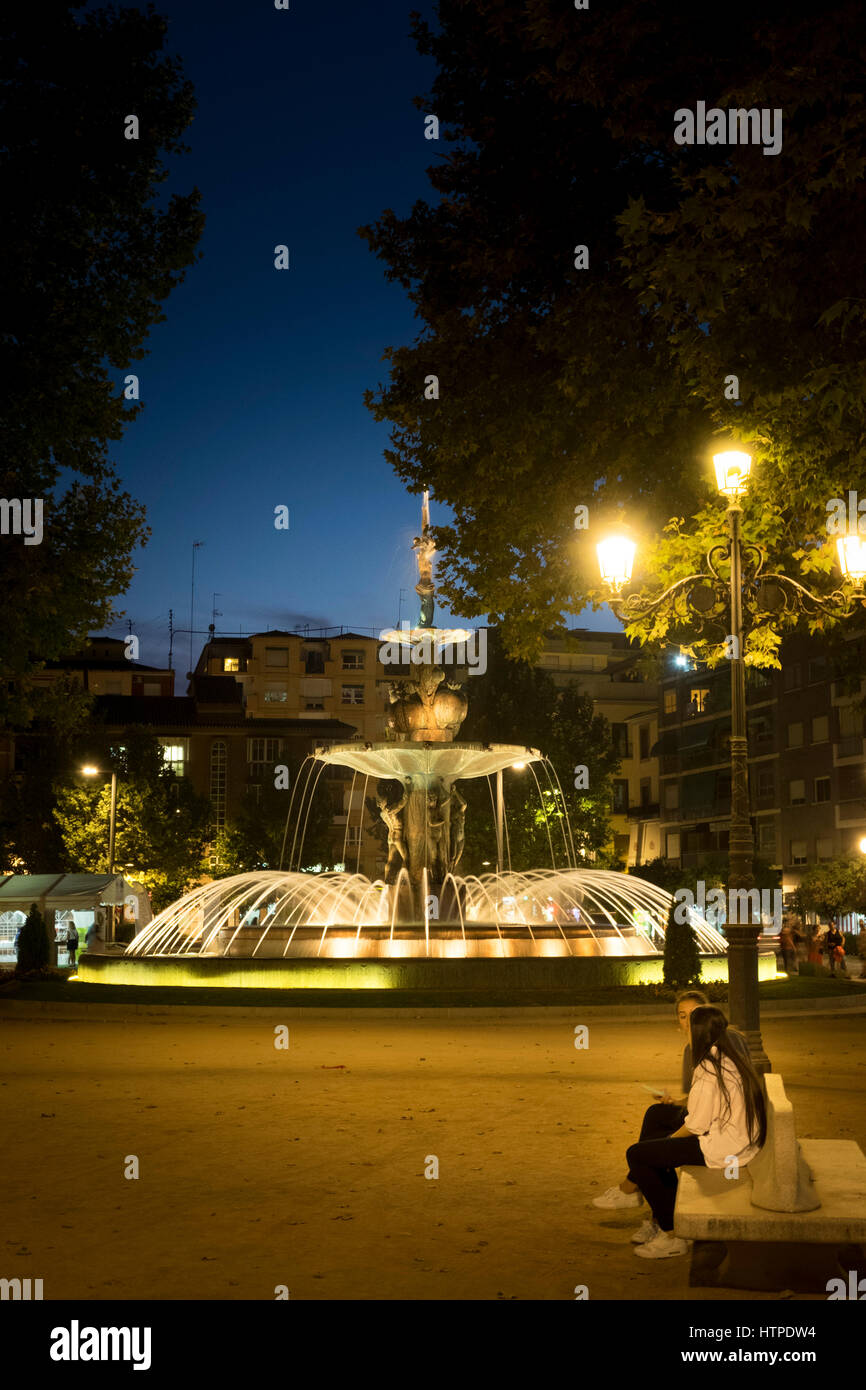 People sitting under street lamp talking by the illuminated Fountain of ...