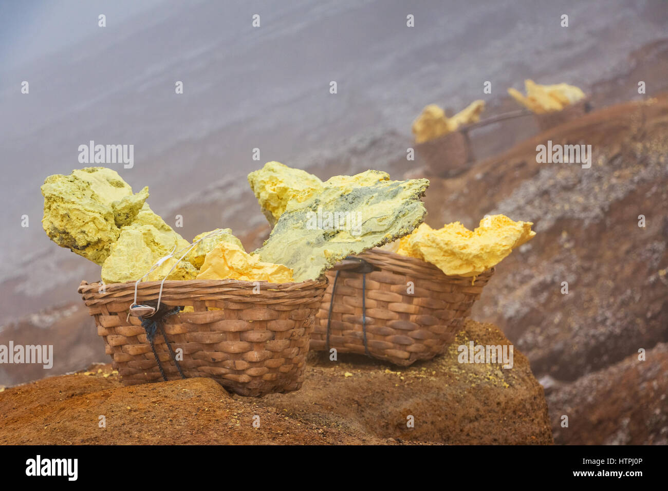Basket filled with sulfur at the open pit mine at Ijen Volcano crater ...