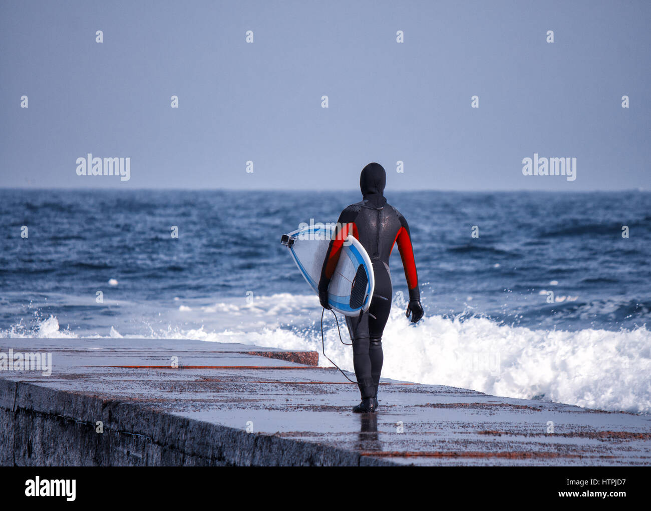 Black wetsuit surfer walks with surfboard hi-res stock photography and ...