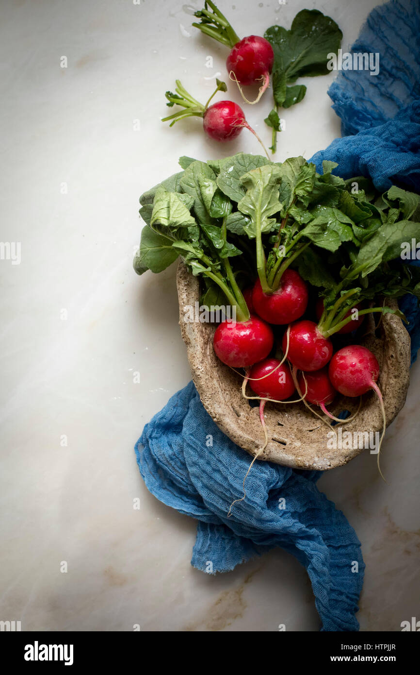 Baby radish in a clay ceramic basket on a white marble background Stock ...