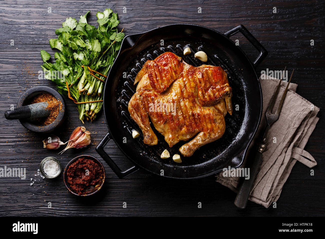 Grilled fried roast Chicken Tabaka in frying pan on wooden background ...