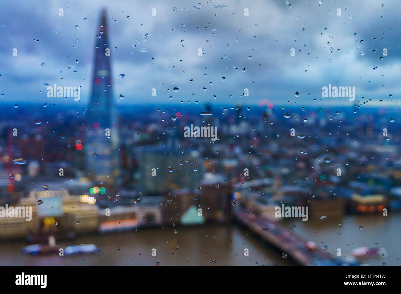 London behind the waterdrops and Thames river at sunset against a ...