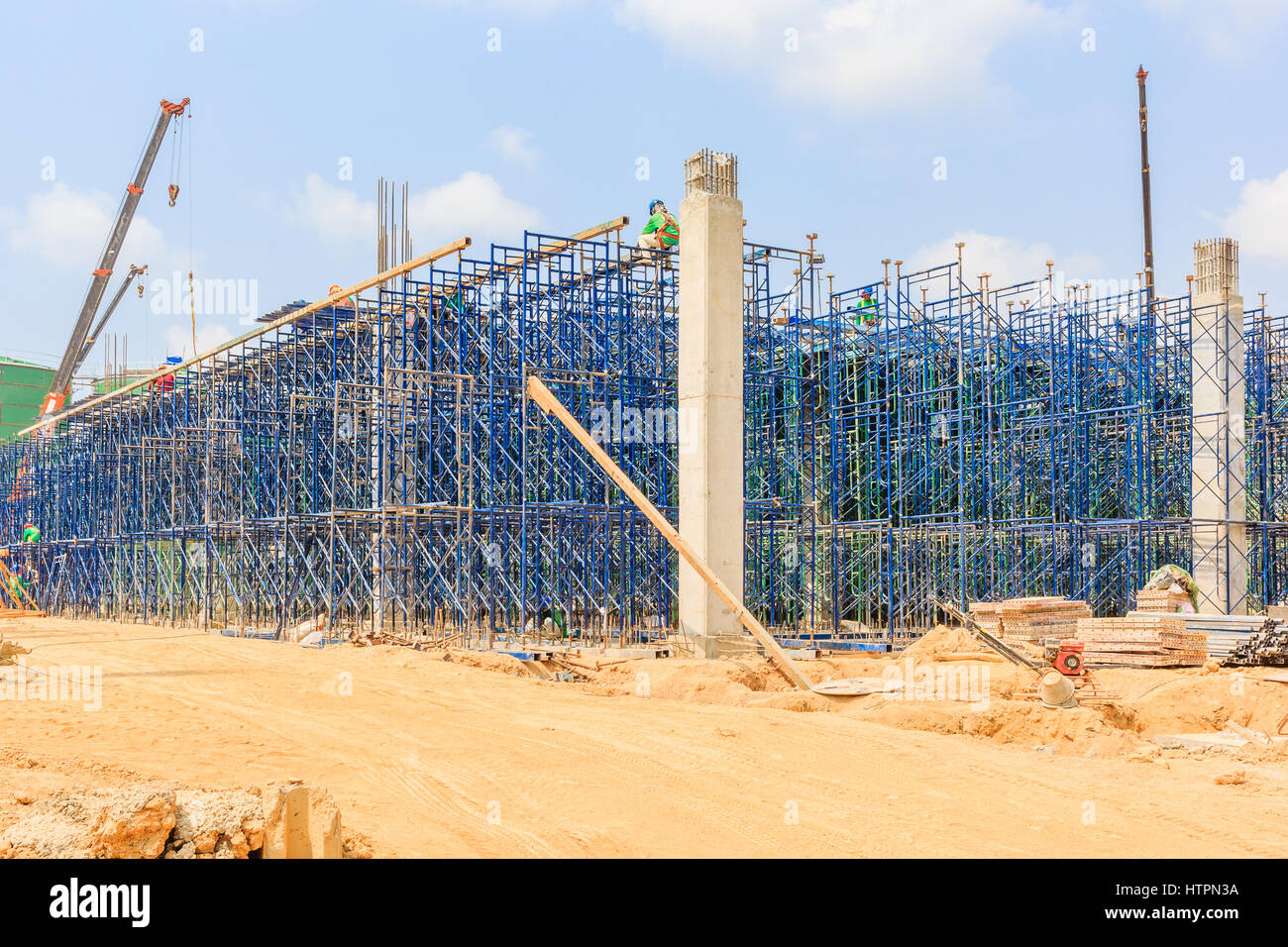 Construction workers wearing safety harness and installing scaffolding ...