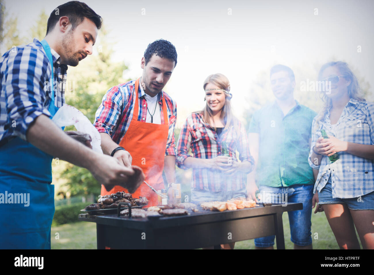 Happy friends grilling meat and enjoying barbecue party outdoors Stock ...