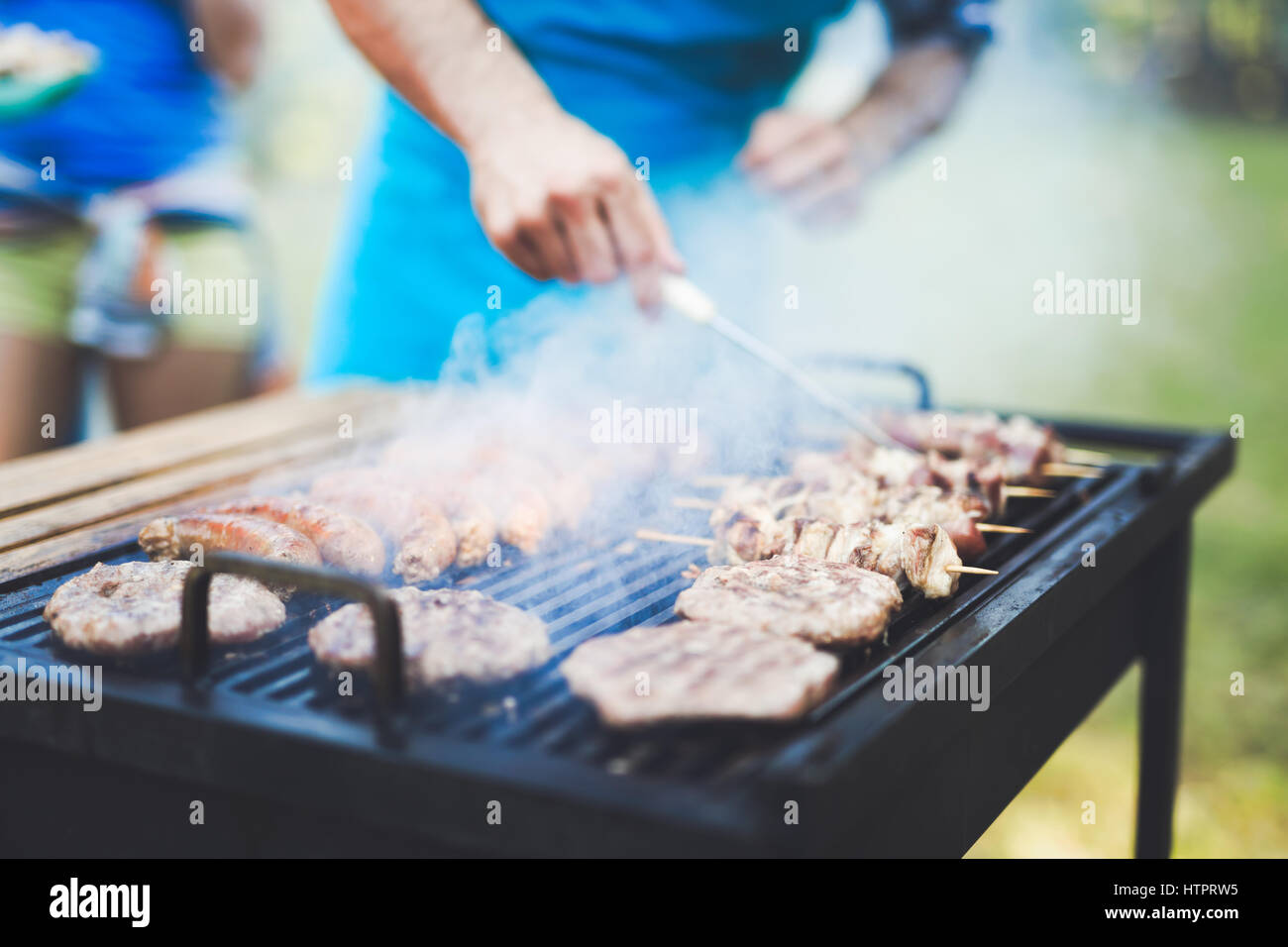 Happy outgoing people enjoying bbq and grilling meat Stock Photo - Alamy