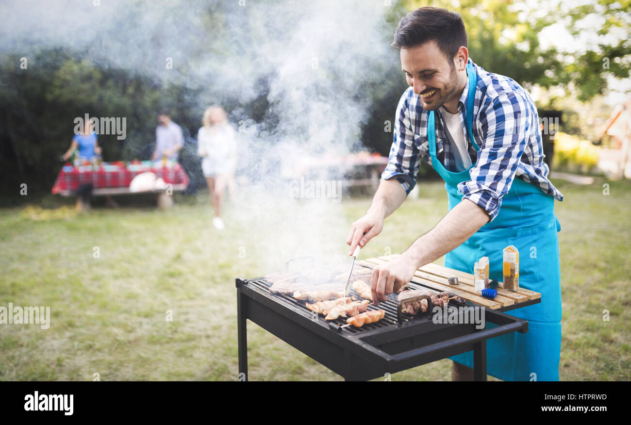 Handsome happy male preparing barbecue outdoors for friends Stock Photo ...
