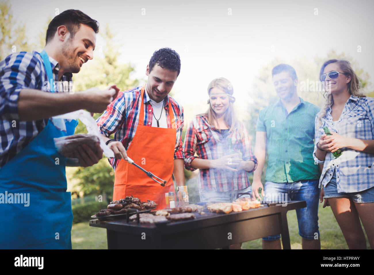 Happy friends grilling meat and enjoying barbecue party outdoors Stock ...