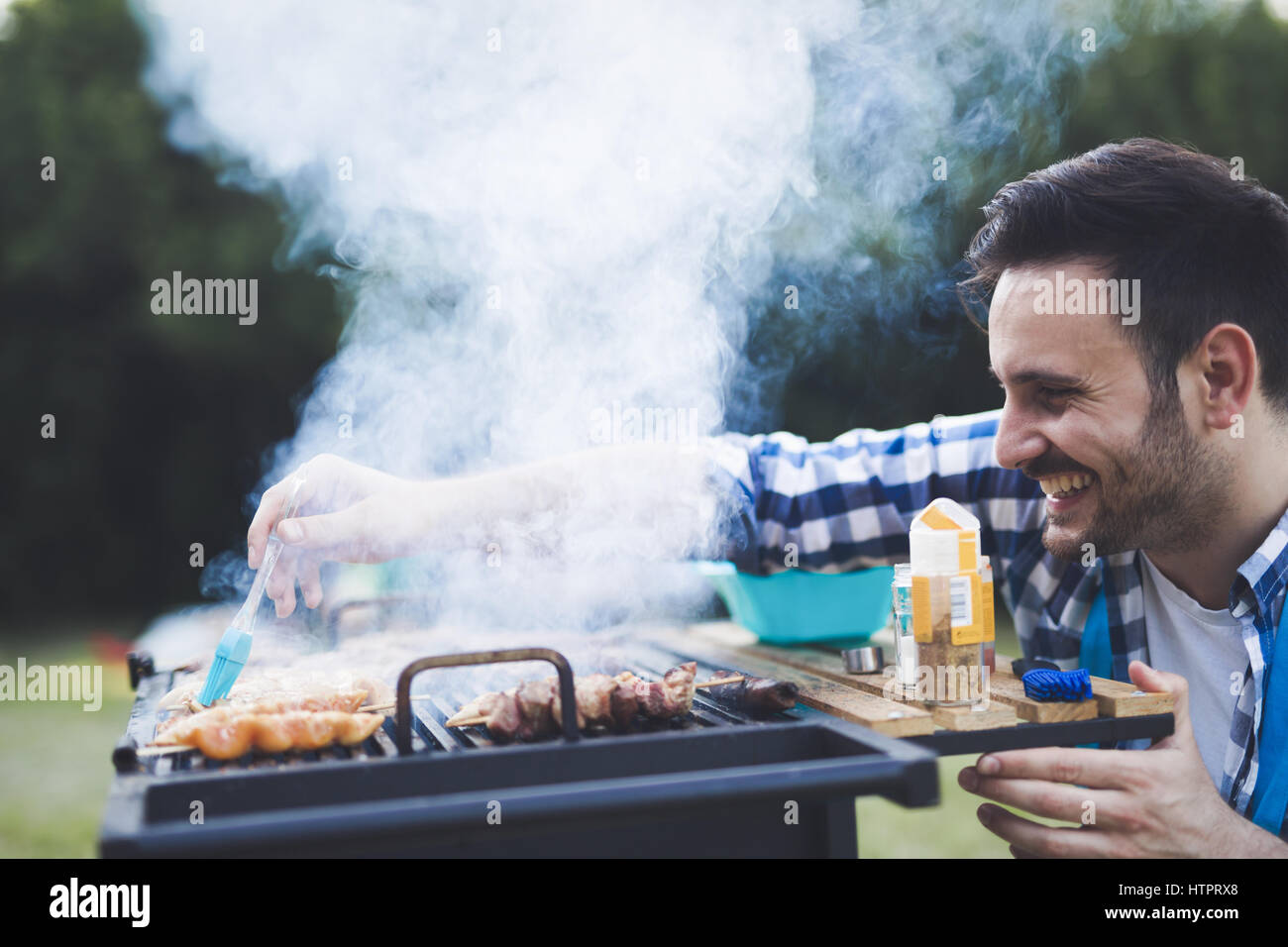 Handsome male grilling meat for barbecue party outdoor Stock Photo - Alamy