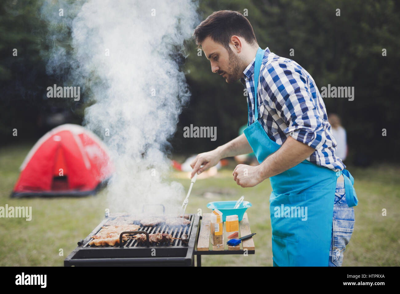 Handsome male grilling meat for barbecue party outdoor Stock Photo - Alamy