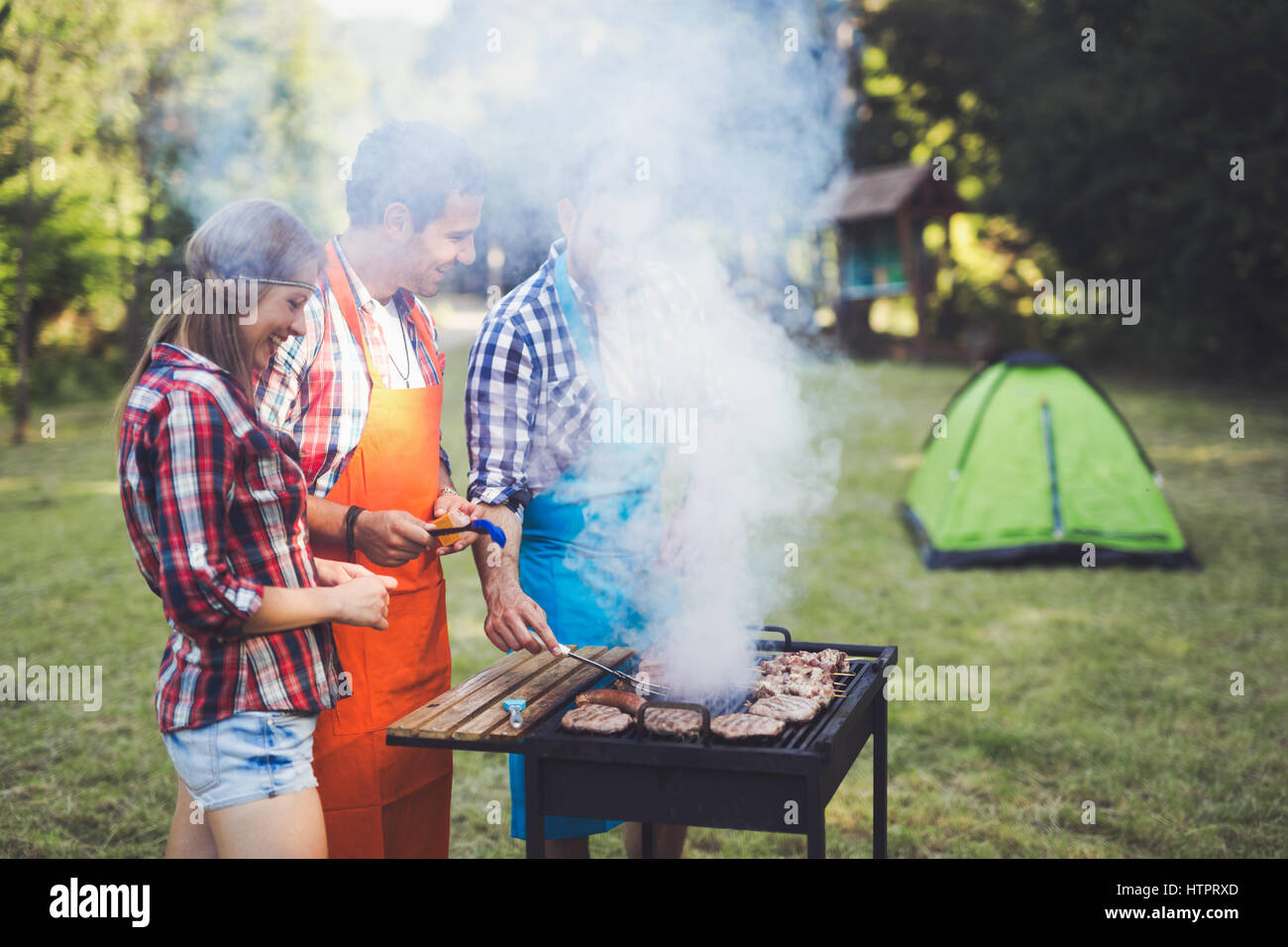 Happy friends grilling meat and enjoying barbecue party outdoors Stock ...