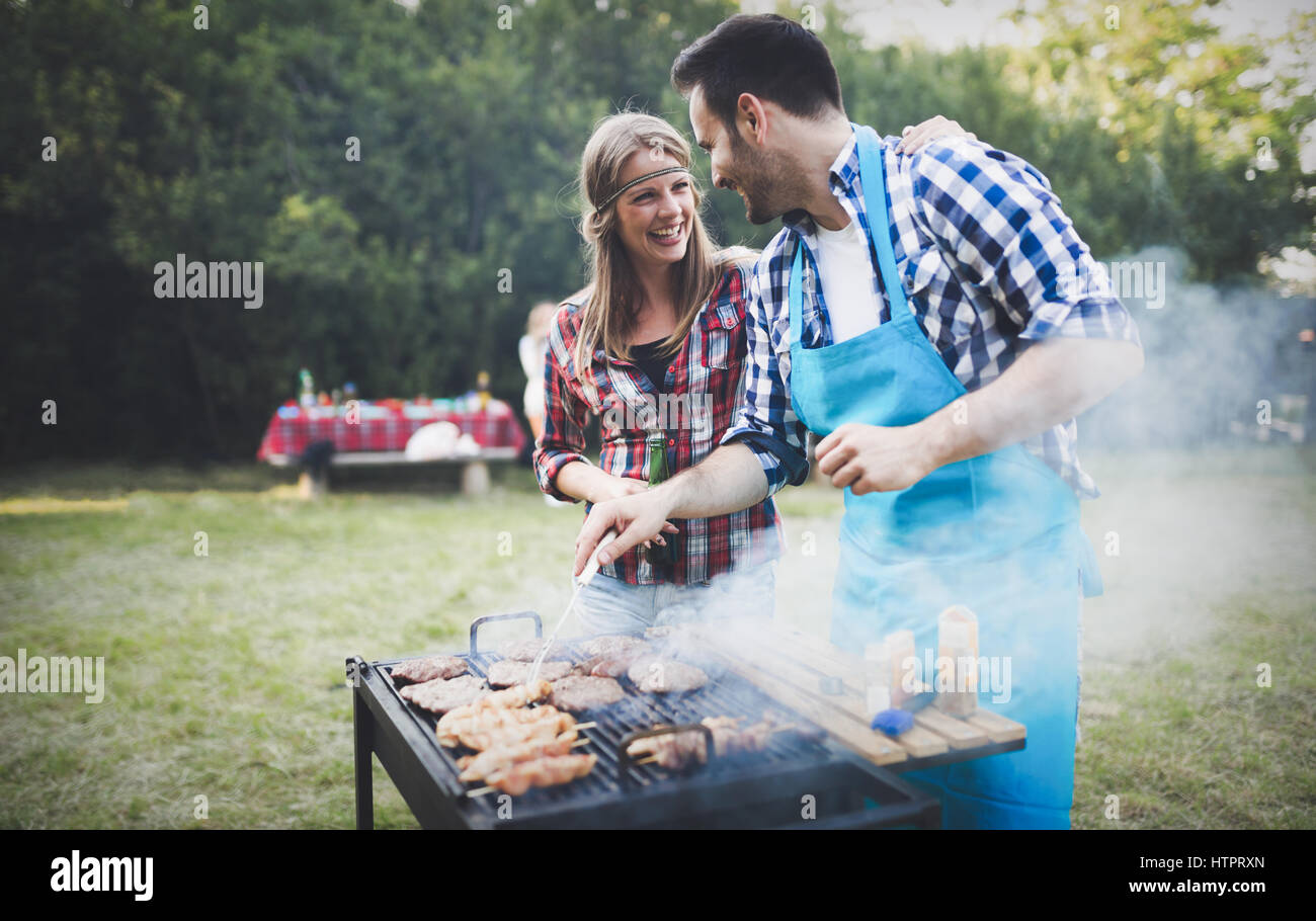 Happy friends grilling meat and enjoying barbecue party outdoors Stock ...