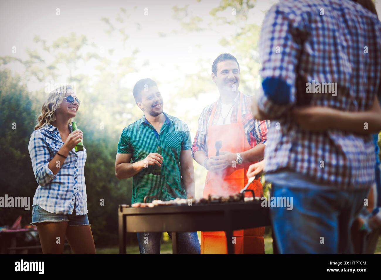 Friends having fun grilling meat enjoying bbq party Stock Photo - Alamy