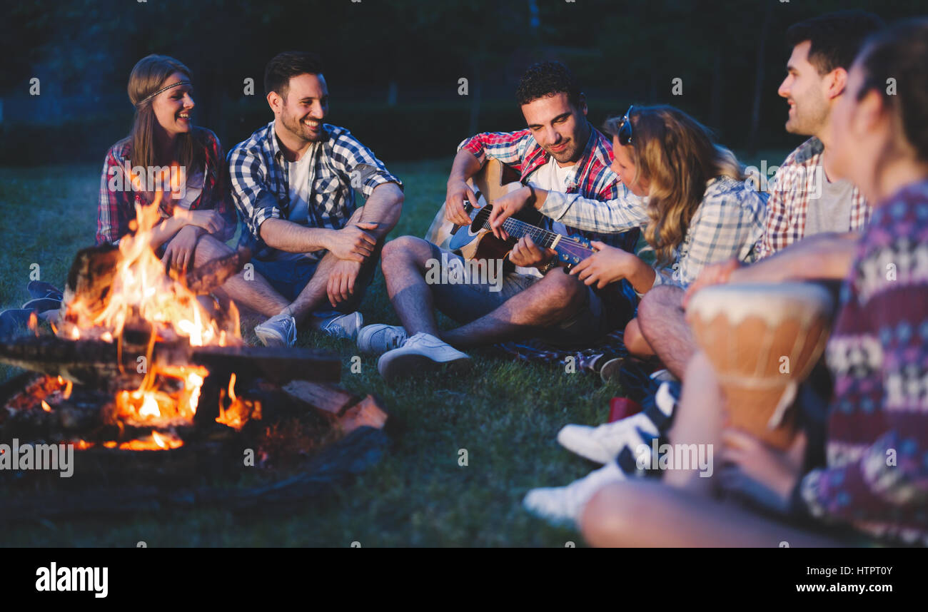 Happy friends playing music and enjoying bonfire in nature Stock Photo ...