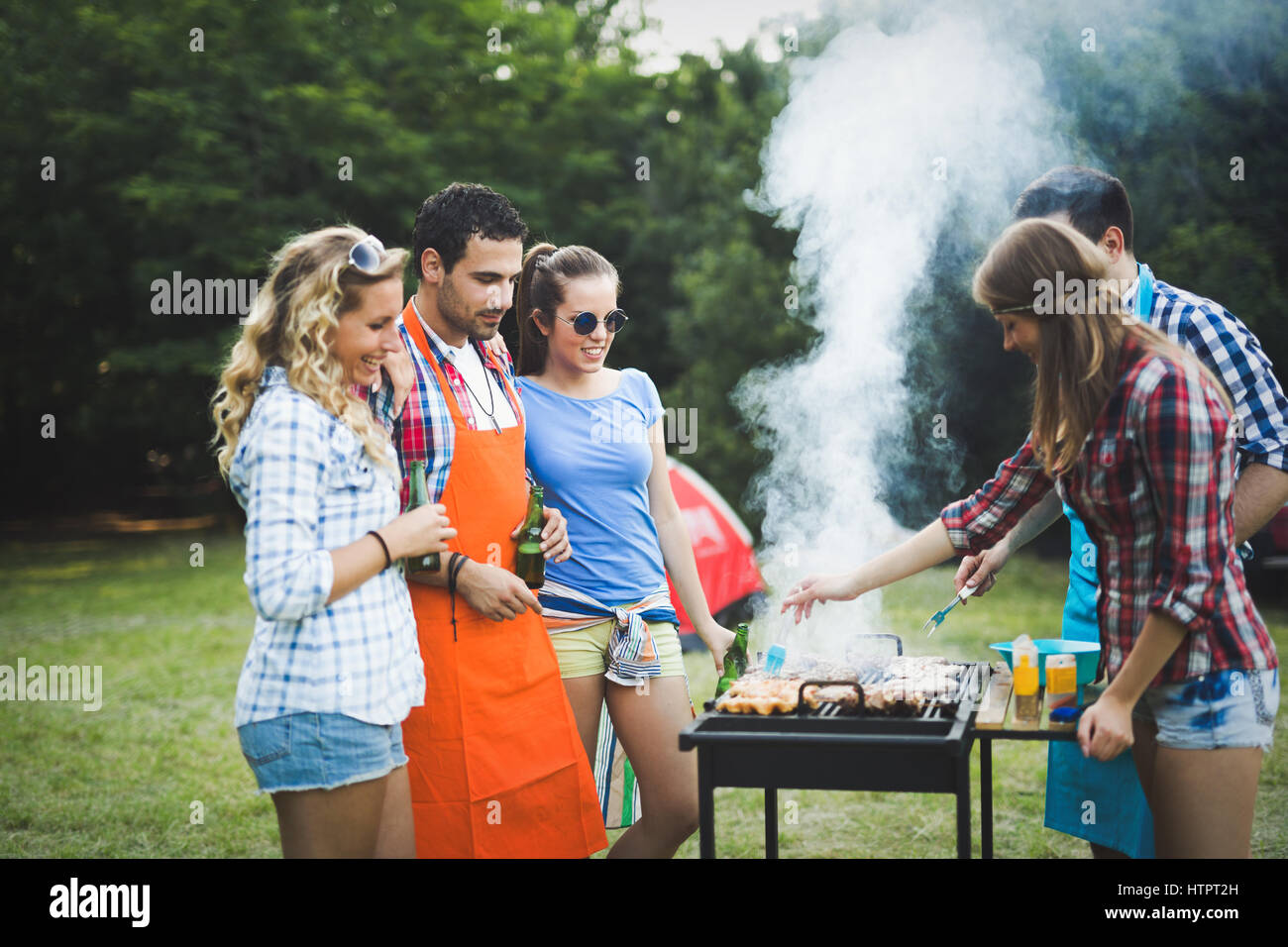 Happy friends grilling meat and enjoying barbecue party outdoors Stock ...