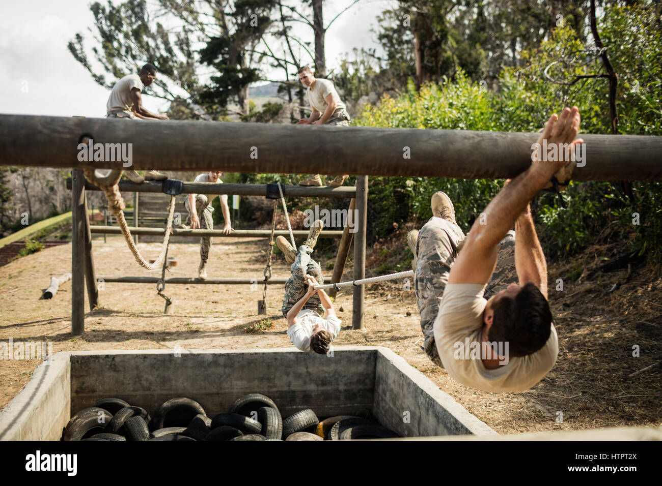 Young military soldiers practicing rope climbing during obstacle course ...
