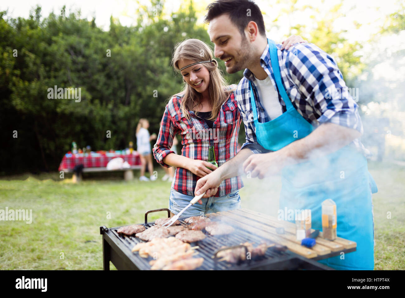 Happy outgoing people enjoying bbq and grilling meat Stock Photo - Alamy
