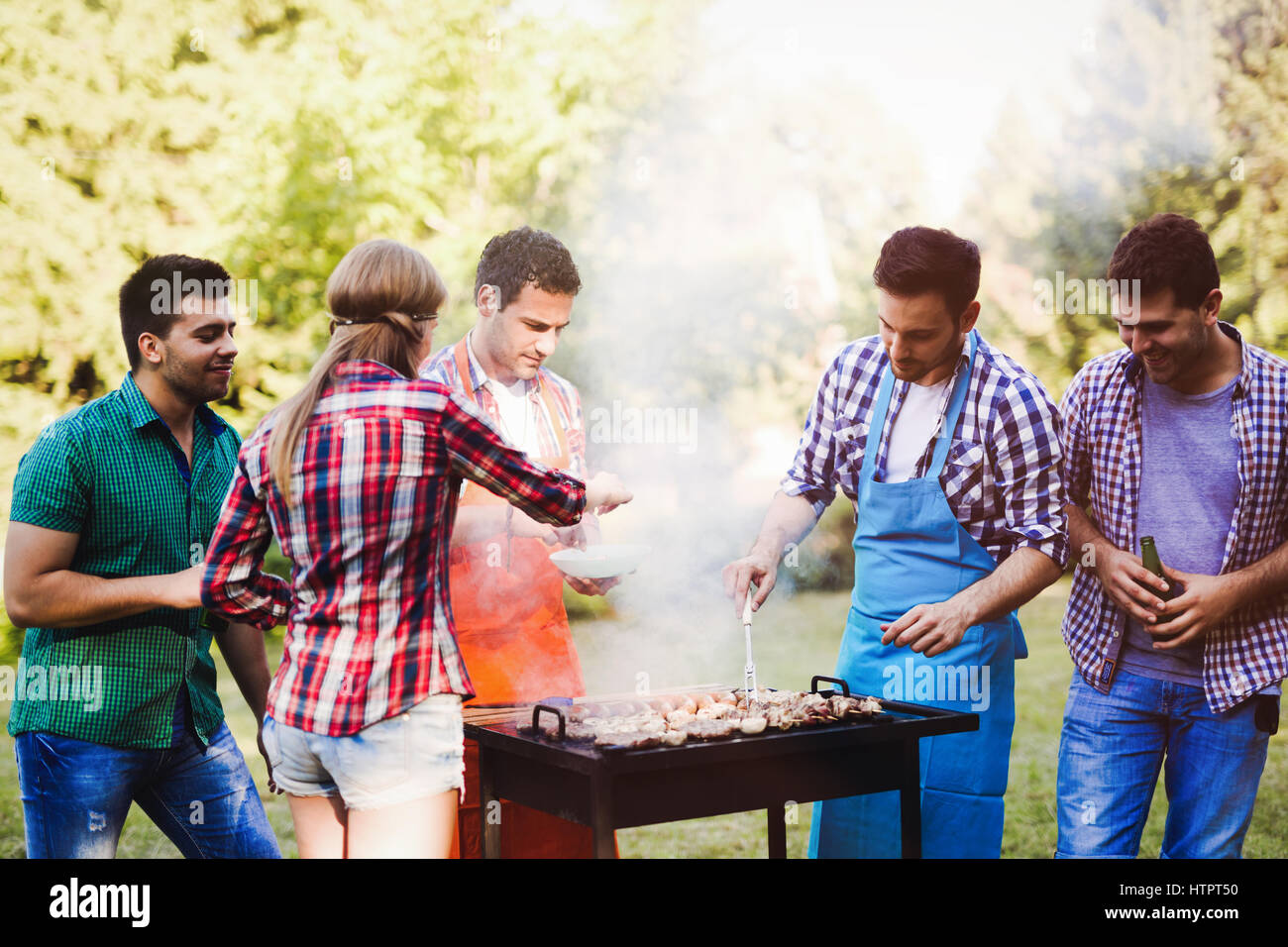 Happy friends grilling meat and enjoying barbecue party outdoors Stock ...